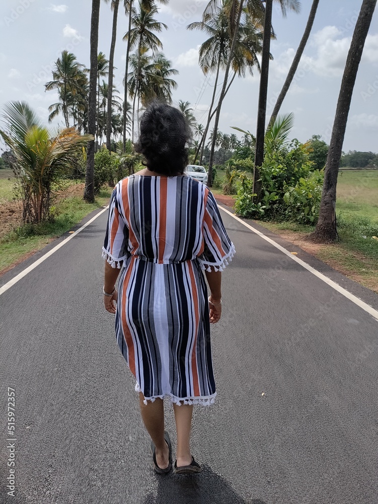 A young girl walking on a famous Parra Coconut road in Goa surrounded ...