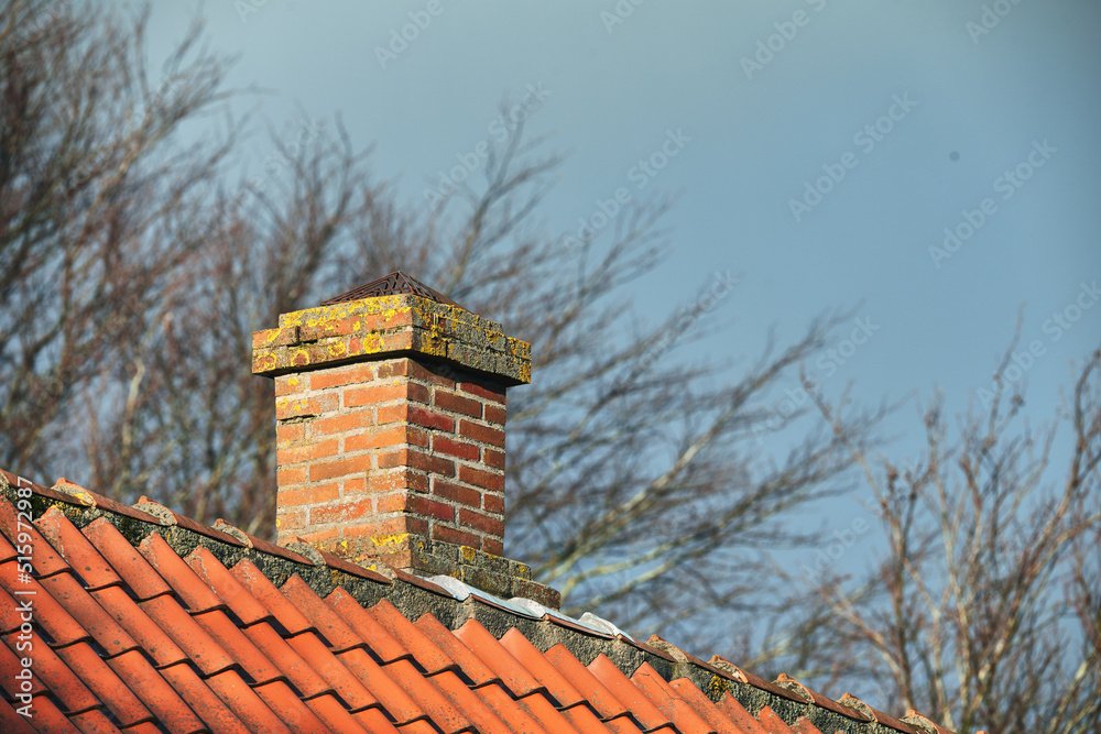 Red brick chimney designed on asbestos slate roof of house building ...