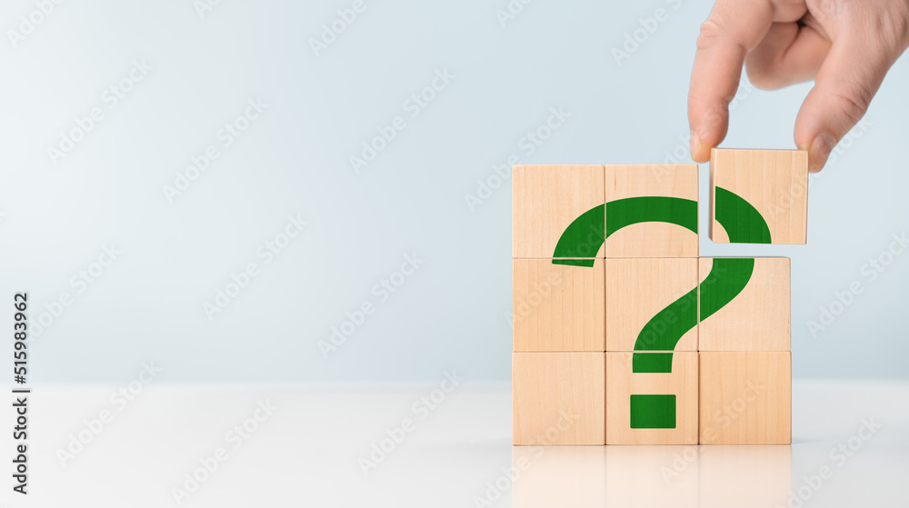 Cubes with green question marks, closeup. Space for text. hand hold ...
