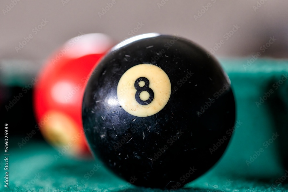 Black billiard ball with the number 8 on a green billiard table with ...