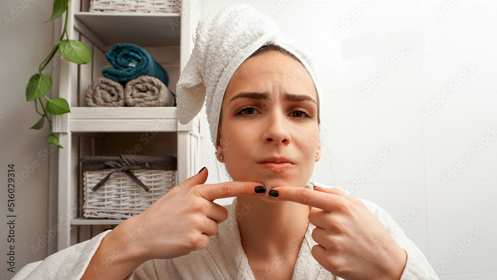 Young woman squeezing a pimple on her face. Hurting face expression ...