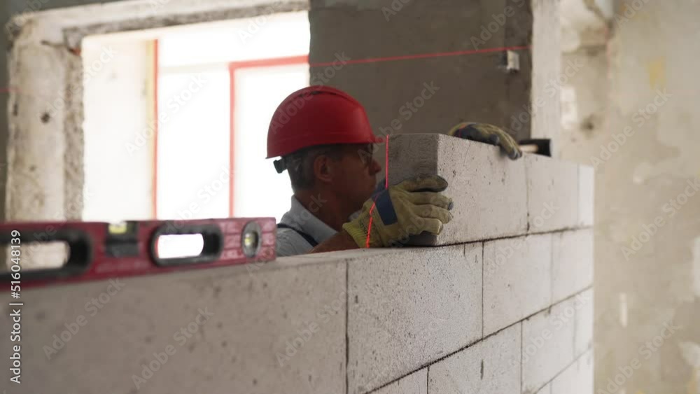 Bricklayer or mason lays bricks to construct wall of autoclaved aerated ...
