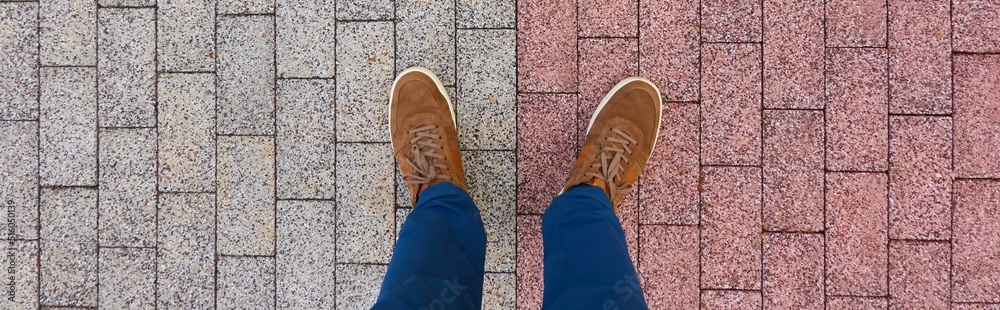 Man standing on granite cobblestone road. Blue jeans and brown boots ...