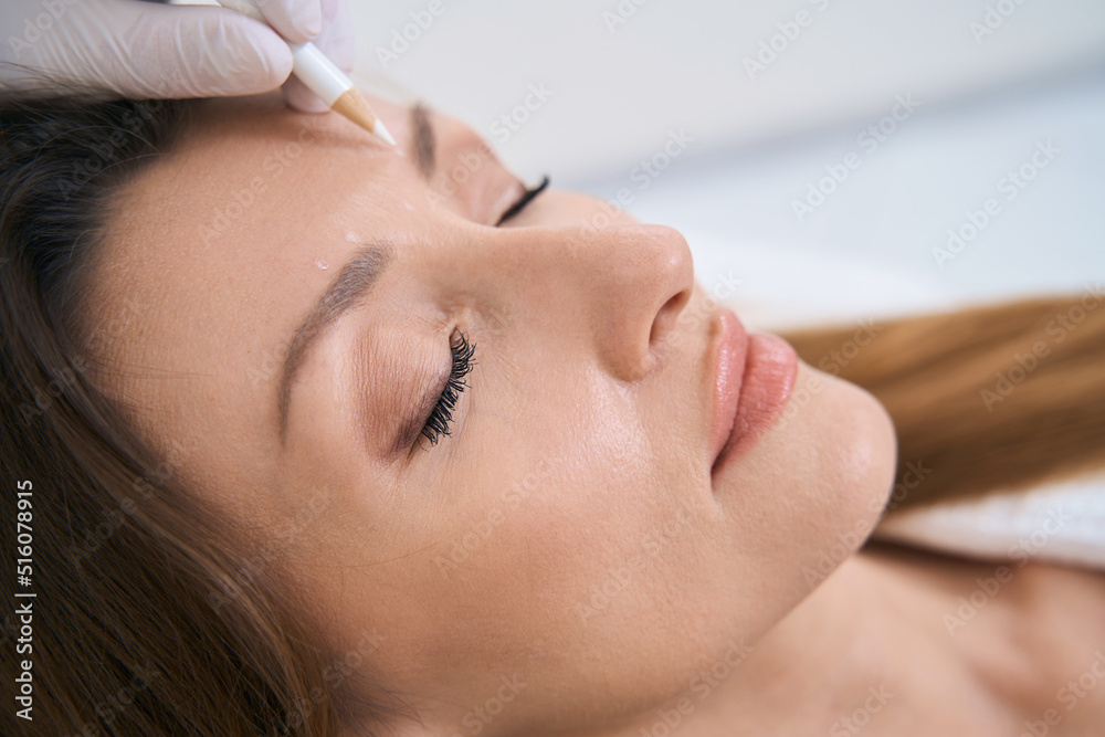 Specialist draws markings on the face of the client before the ...