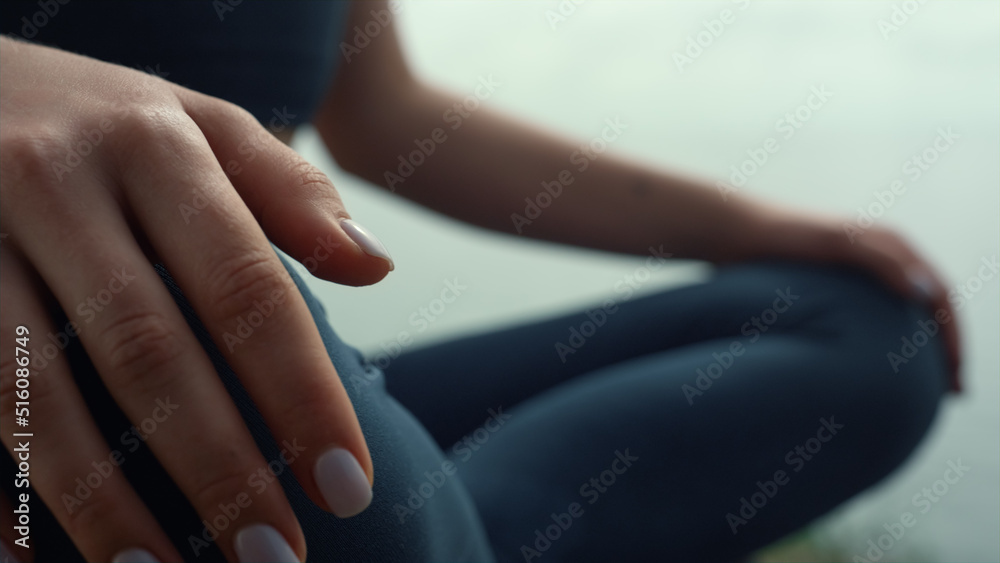 Fit girl practicing lotus pose on sea beach closeup. Woman hand lie on ...