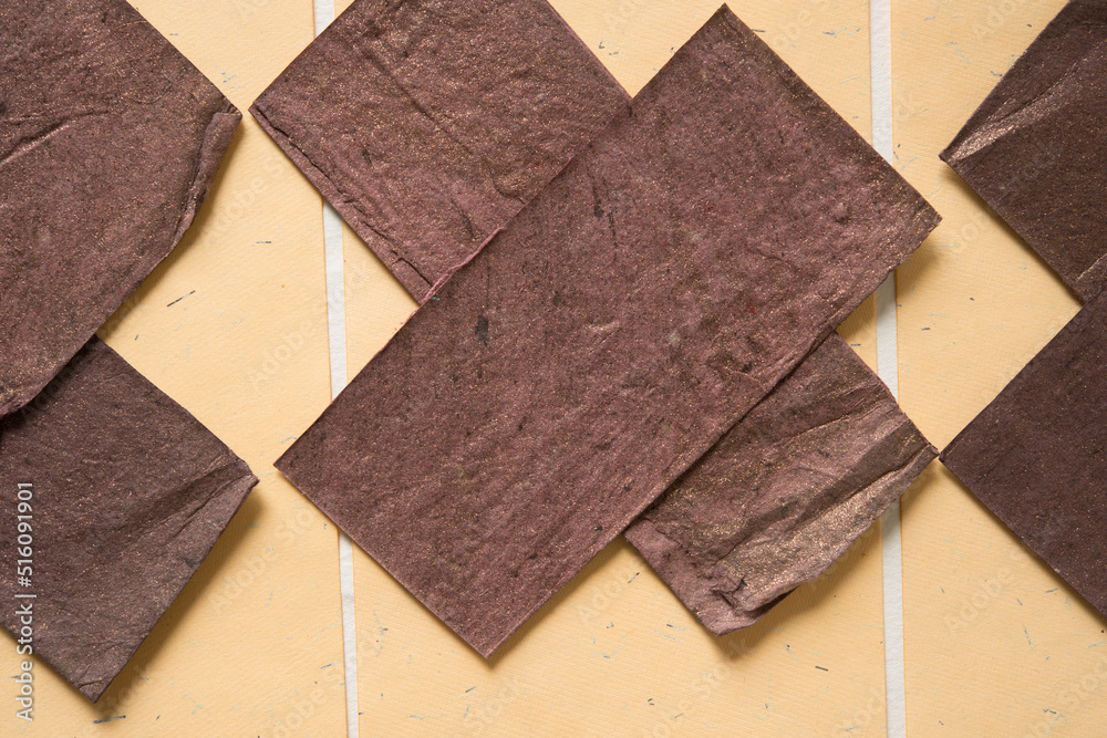 bronze or brown paper with shiny surface arranged in X forms on yellow ...