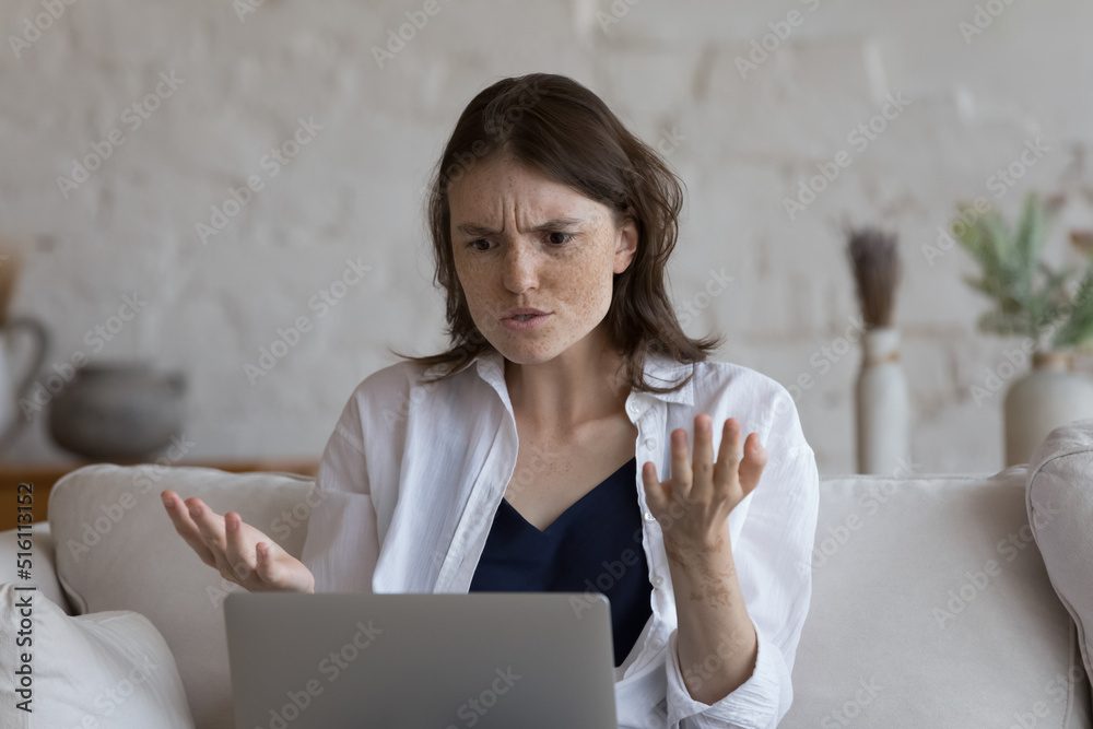 Young frown woman sit on sofa staring at laptop feels angry due broken ...