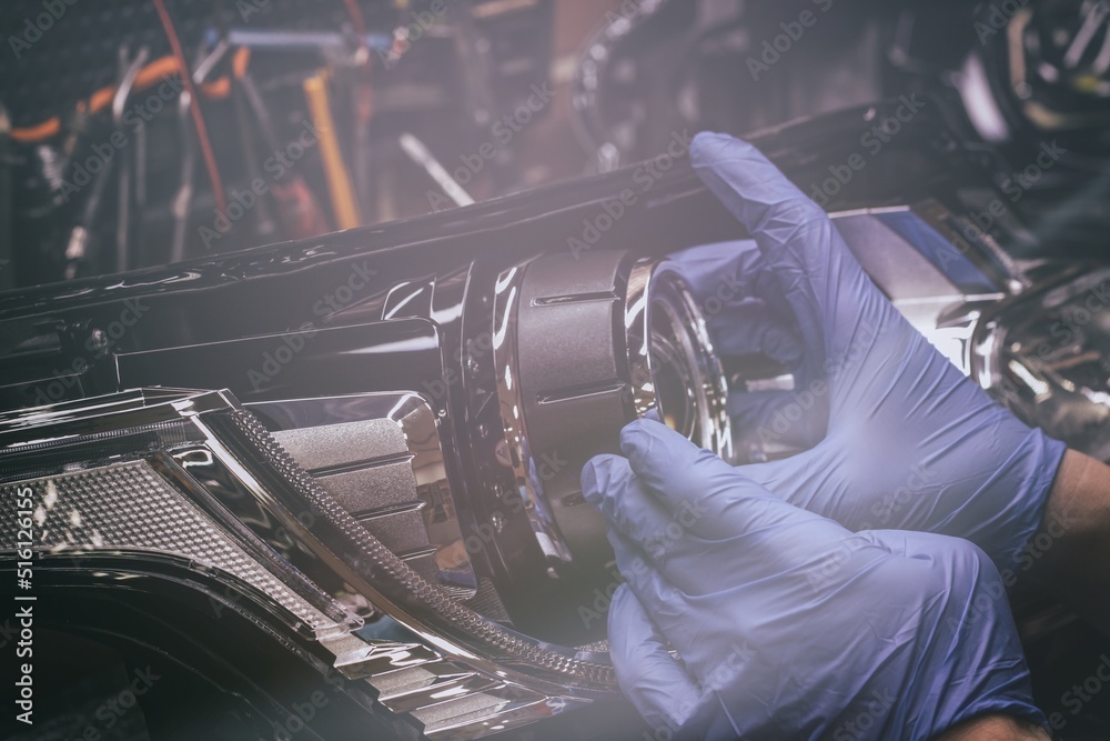 Car headlight in repair close-up. The car mechanic installs the lens in ...