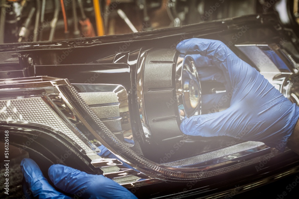 Car headlight in repair close-up. The car mechanic installs the lens in ...