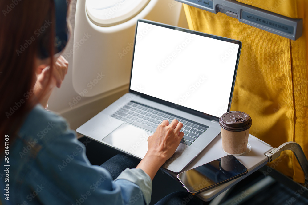 An Asian woman sits in a window seat in Economy Class using a white ...