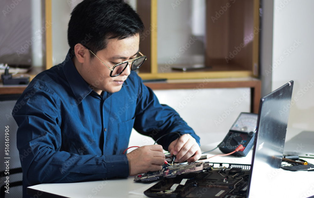 young man who is a computer technician A laptop motherboard repairman ...