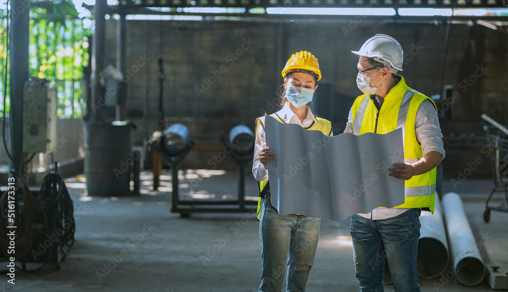 male and female engineers Spreading the floor plan inside the factory ...