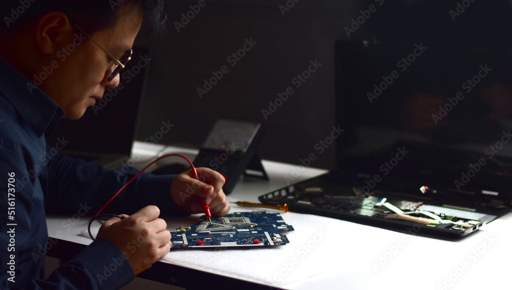 young man who is a computer technician A laptop motherboard repairman ...
