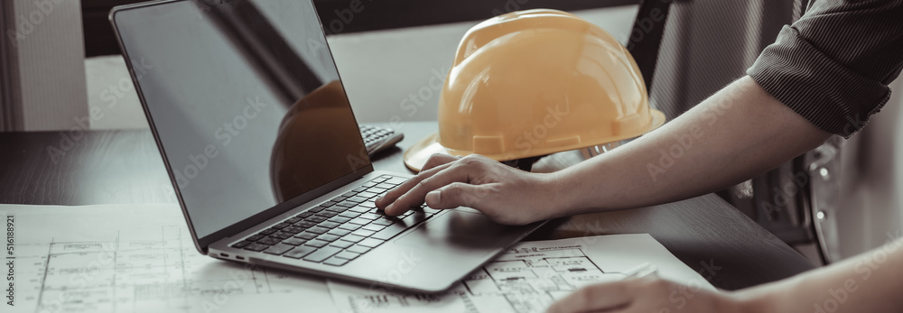 Young man with a laptop plotting a system of building structures in ...