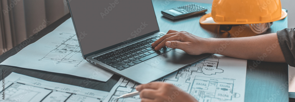 Young man with a laptop plotting a system of building structures in ...