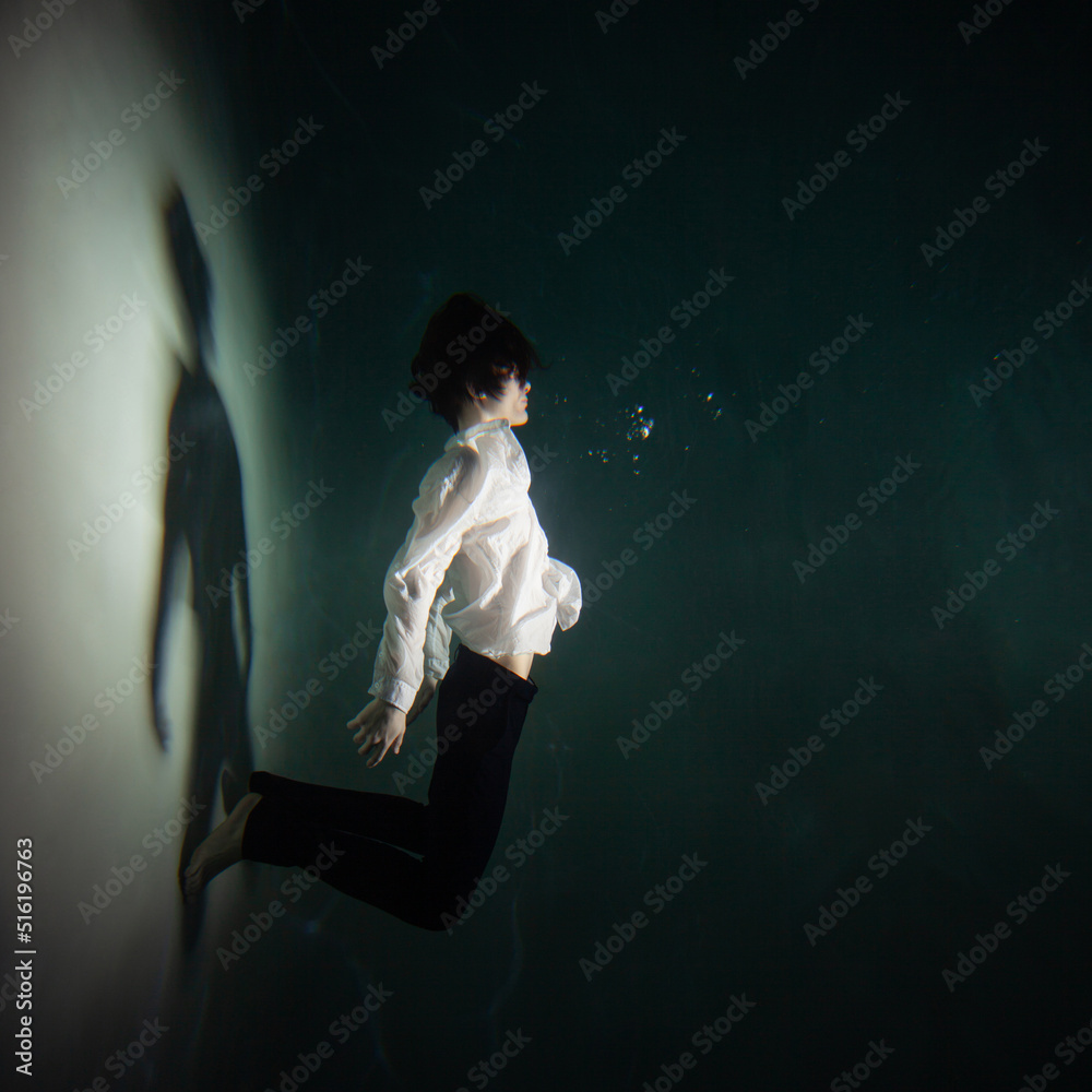 Beautiful underwater shooting, guy in white shirt and pants has fallen ...