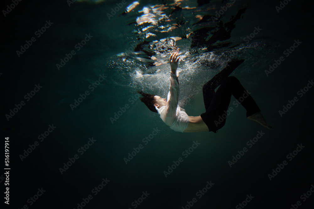 Beautiful underwater shooting, guy in white shirt and pants has fallen ...