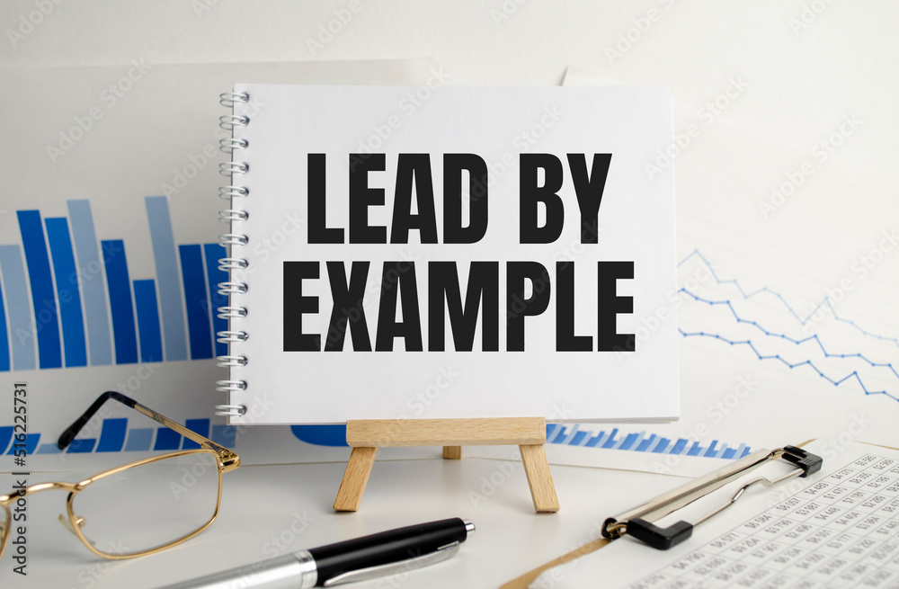 lead by example, text on white paper on the light background with ...