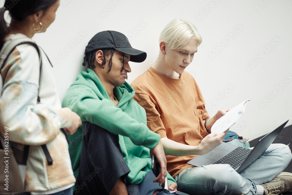 Two intercultural teenage guys looking through lecture notes in ...