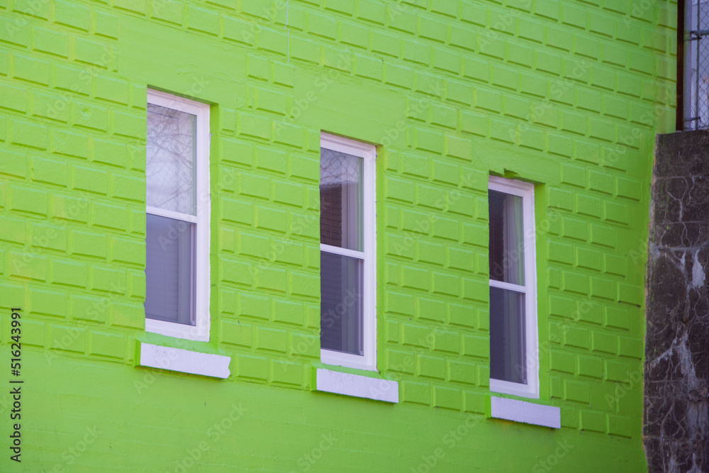 A vibrant lime green block exterior wall of a building with three long ...
