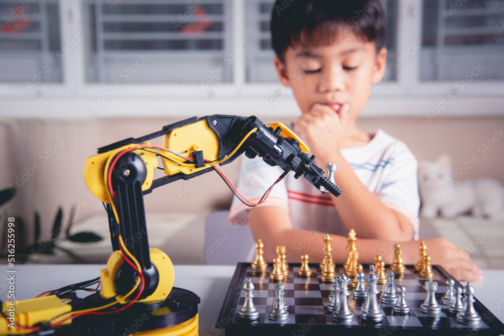 Asian little boy thinking and wait robot arm playing chess, STEM ...
