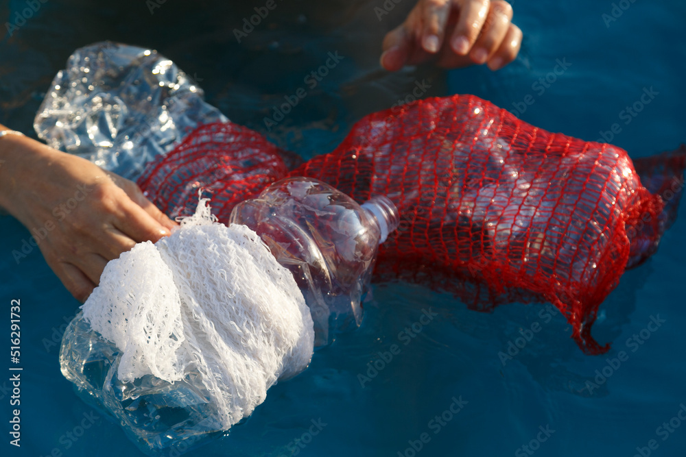 Recogiendo botellas de plástico y saco de red flotando en el agua Stock ...