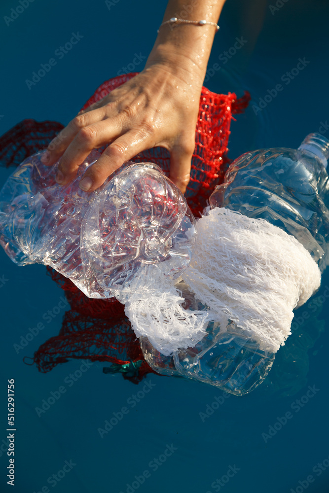 Recogiendo botellas de plástico y saco de red flotando en el agua Stock ...