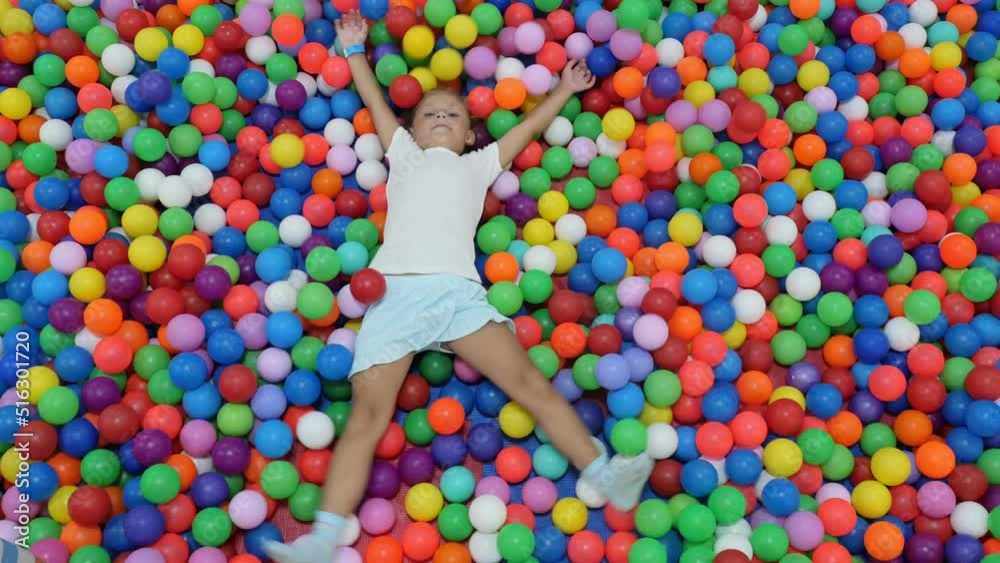 Vídeo do Stock: little girl lying on multi coloured plastic balls in ...