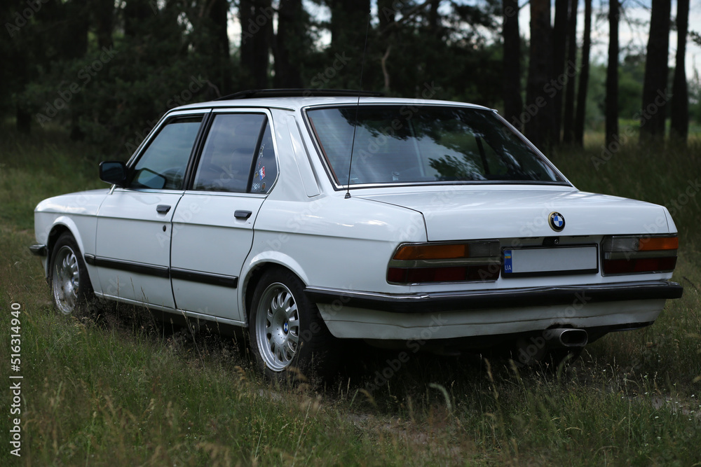 Rear and side view of a white classic business class sedan - BMW 520i ...