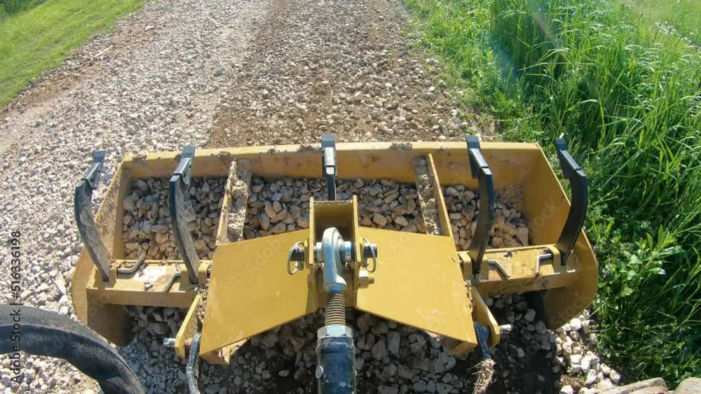 Box scrapper leveling a new graveled driveway and gravel that is in the ...