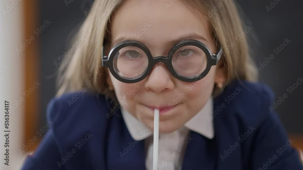 Headshot of nerd schoolgirl in high dioptres eyeglasses drinking juice ...