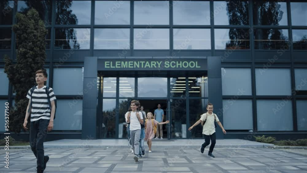 Pupils leaving elementary school building. Children smiling walking ...