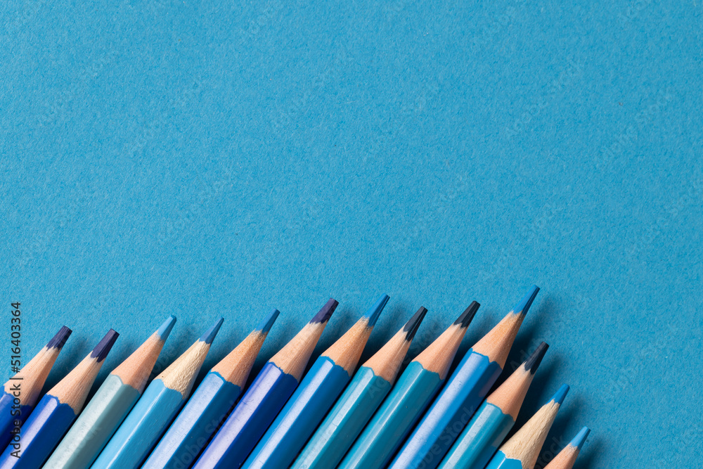 Image of row of different shades of blue crayons on blue background ...