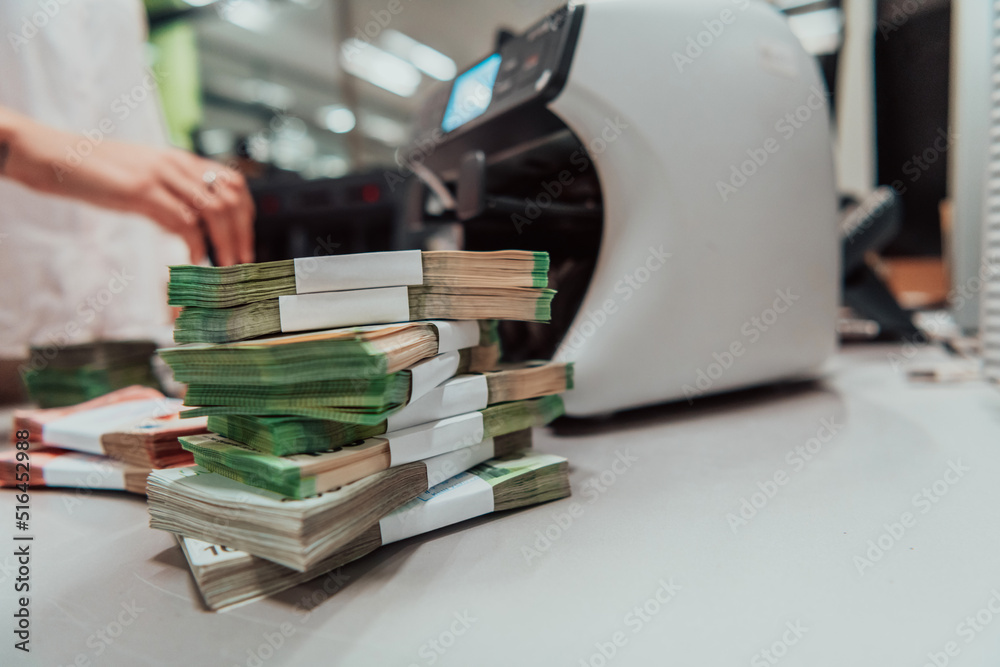 Bank employees using money counting machine while sorting and counting ...