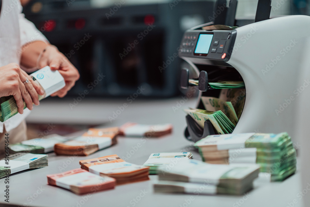 Bank employees using money counting machine while sorting and counting ...