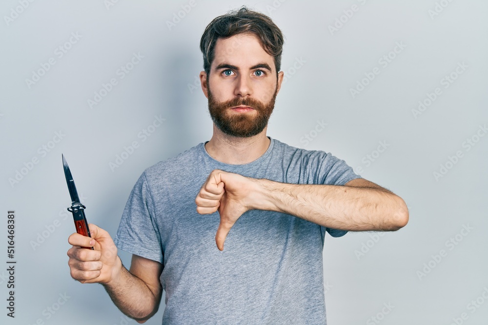 Caucasian man with beard holding pocket knife with angry face, negative ...
