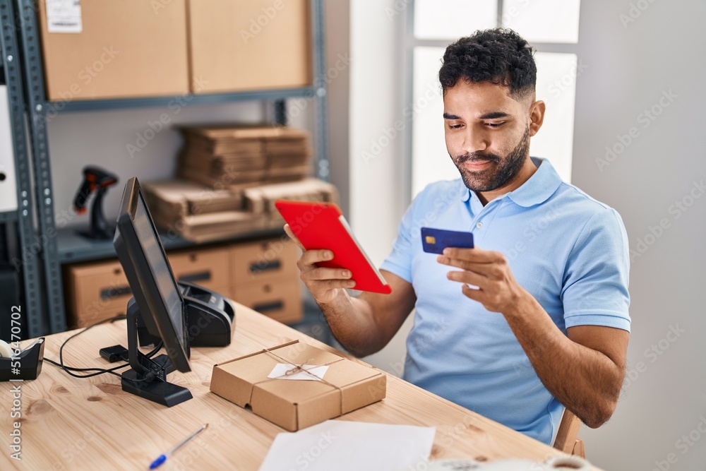 Young hispanic man ecommerce business worker using touchpad and credit ...
