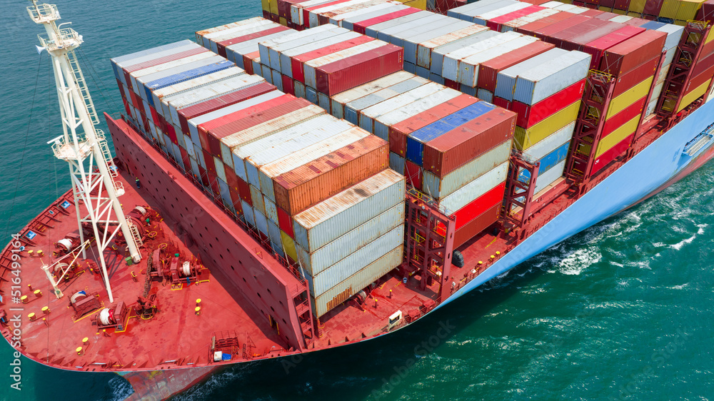 Aerial side view of cargo ship carrying container and running with tug ...
