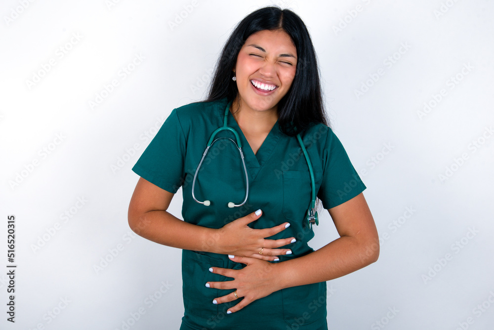 Doctor hispanic woman wearing surgeon uniform over white wall smiling ...