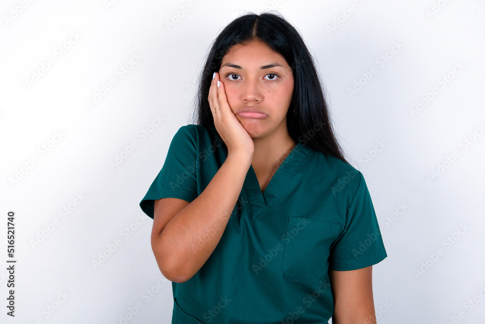 Sad lonely Doctor hispanic woman wearing surgeon uniform over white ...