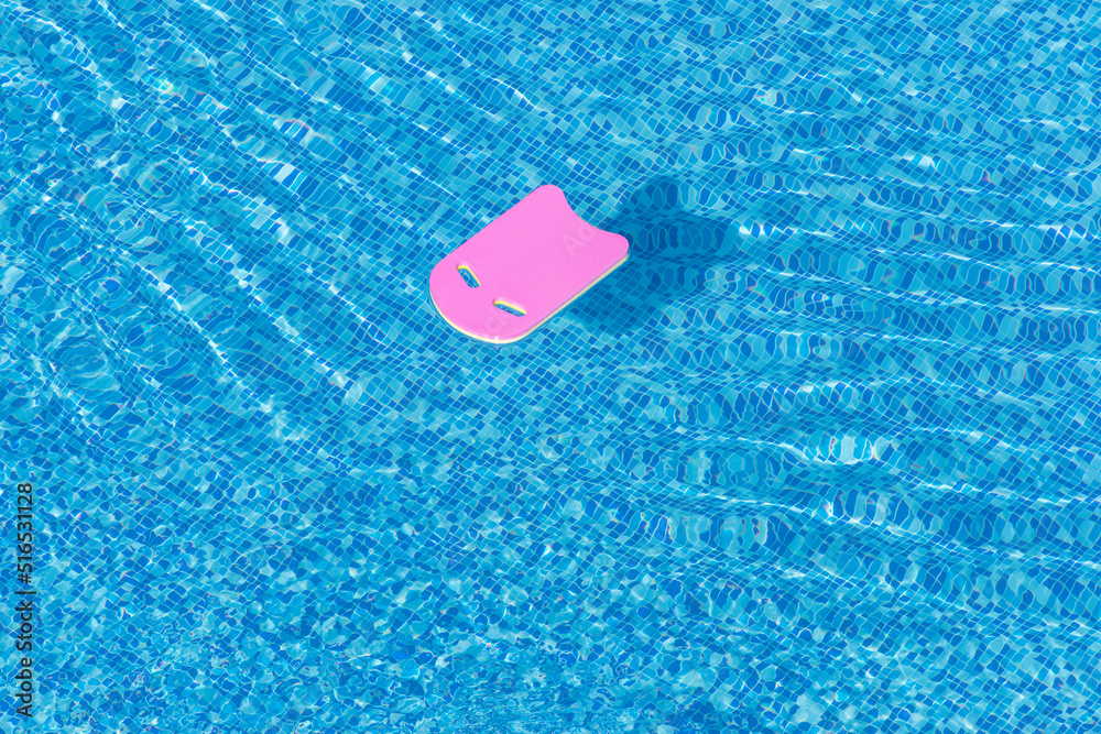 Swimming pool summer background with pink swim board floating on blue ...