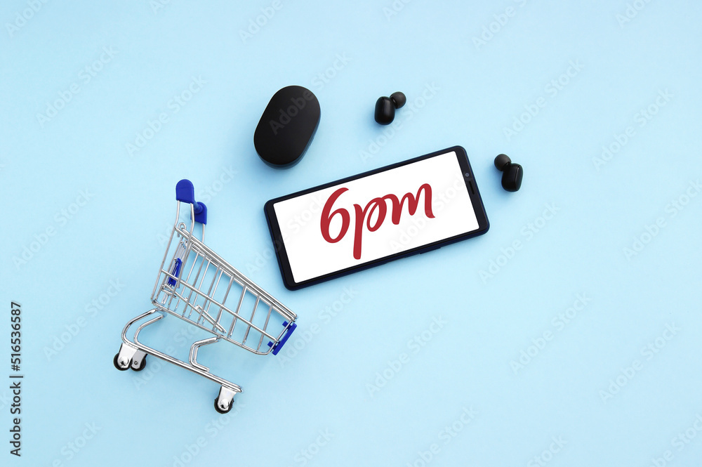 Shopping cart with a smartphone opened 6pm logo on the screen on a blue ...