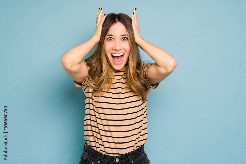Brunette woman looking excited and surprised in a studio with blue ...