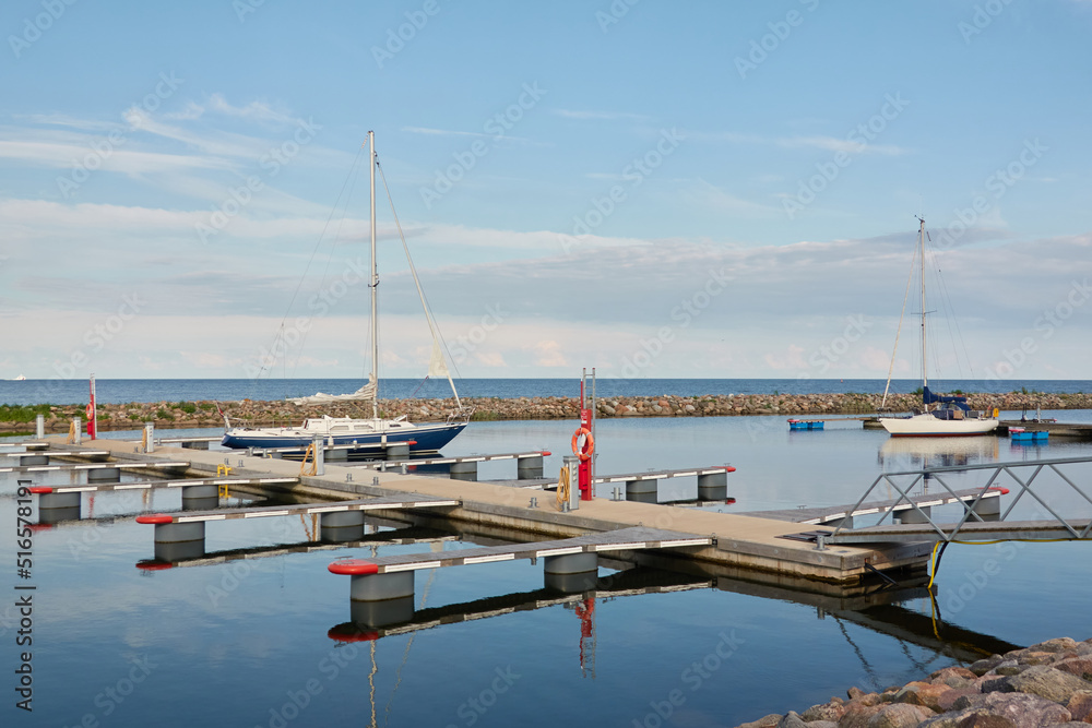 Sloop rigged sailboat (for rent and sale) moored to a pier in a yacht ...