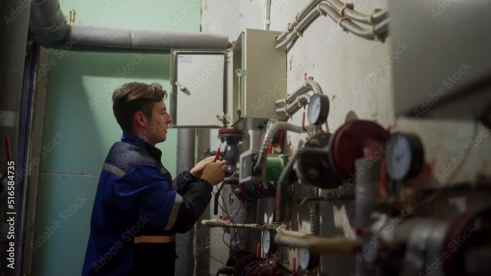 Electrician inspecting electrical fuse box. Master in uniform screwing ...