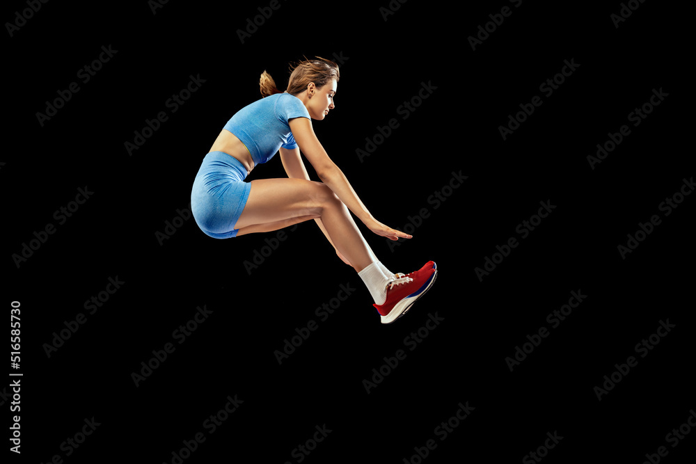 Young sportive girl, long jumper in sports blue uniform performs triple ...