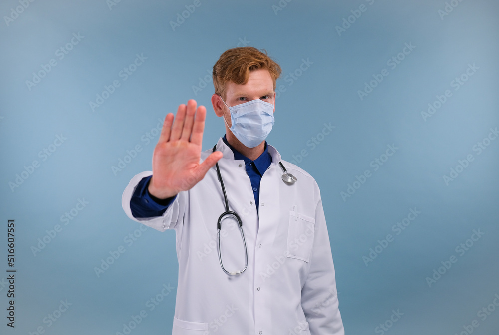 medical male Doctor wear a mask shows a stop sign isolated on blue ...