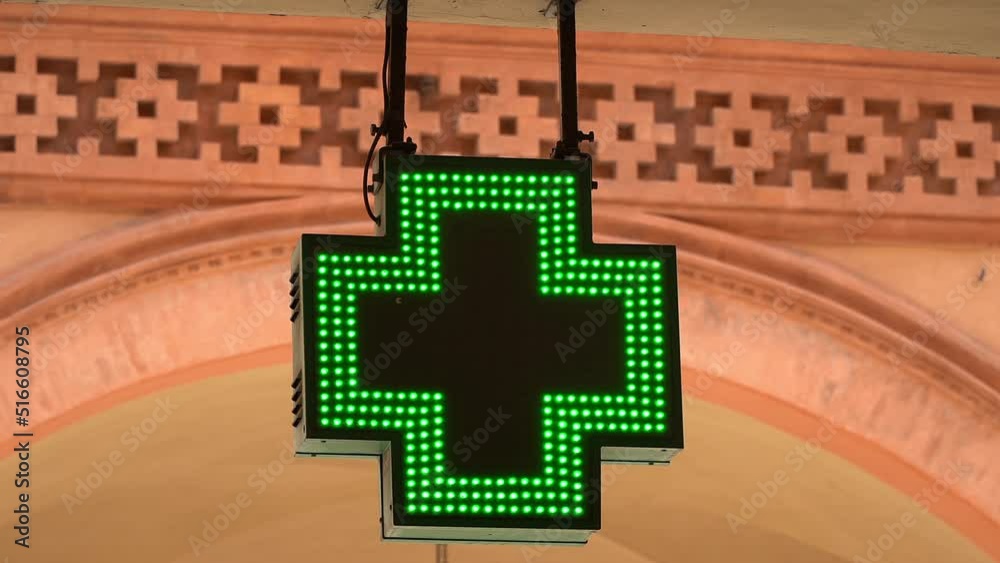A flashing, green, LED cross as a symbol of a pharmacy, helping the ...