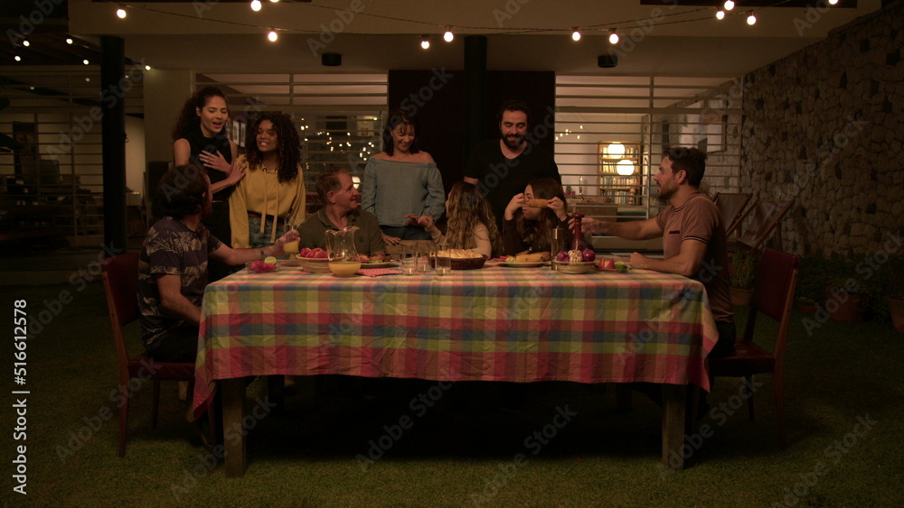 Group of happy people together at night in home backyard laughing and ...