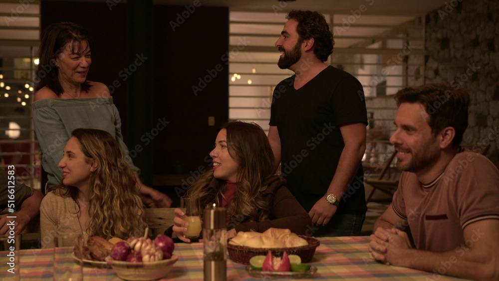 Family and friends at night together around table in backyard in ...
